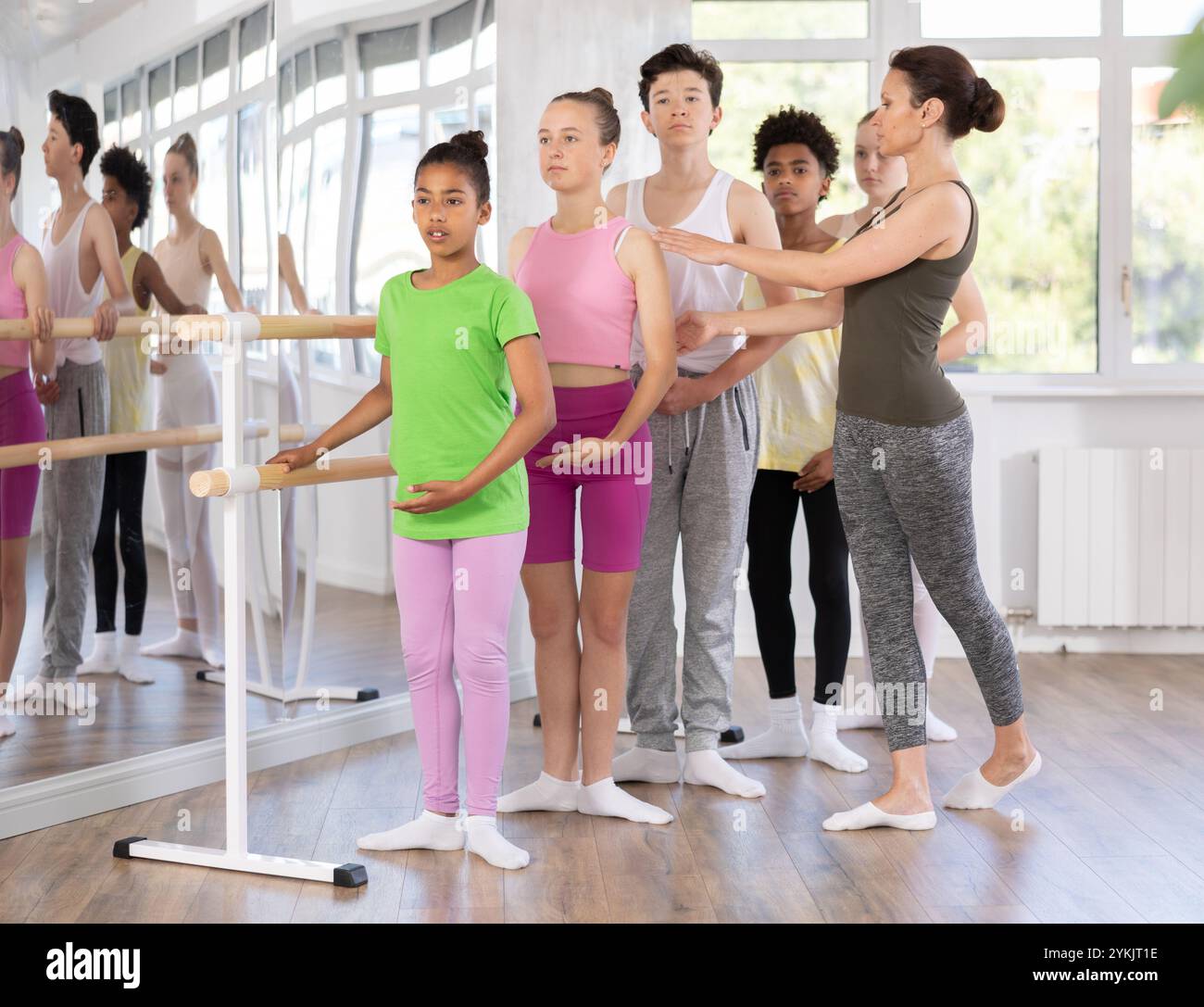 African American teen girl mastering first ballet position at barre ...