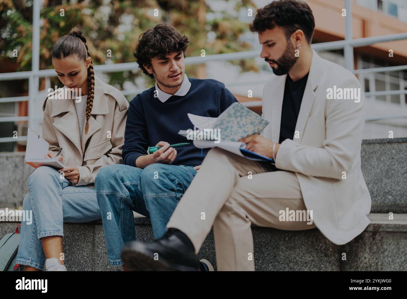 Students collaborating with professor outdoors on academic project ...