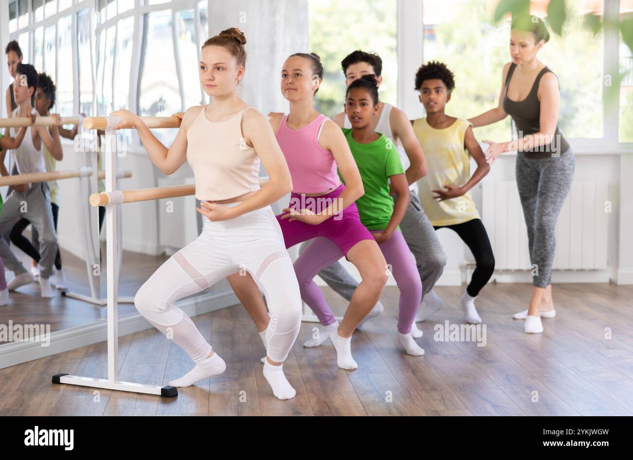 Teenage girl learning grand plie at barre at group ballet class Stock ...