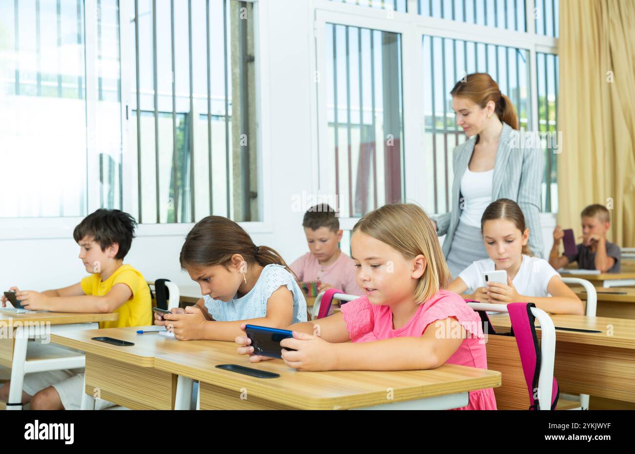 Absorbed preteen school children using mobile phones at lesson Stock ...