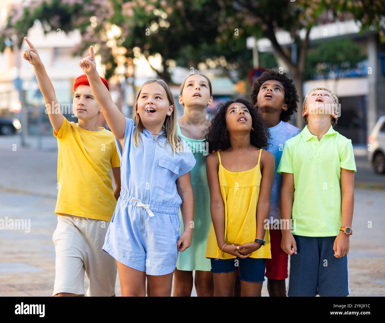 Inquisitive carefree tweens looking up at sky and pointing at something ...
