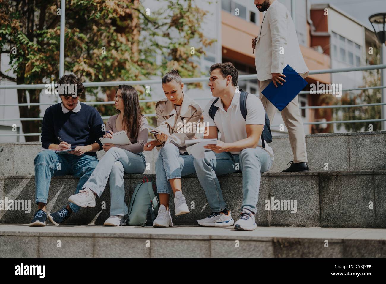 High school students studying outdoors with teacher's assistance Stock ...