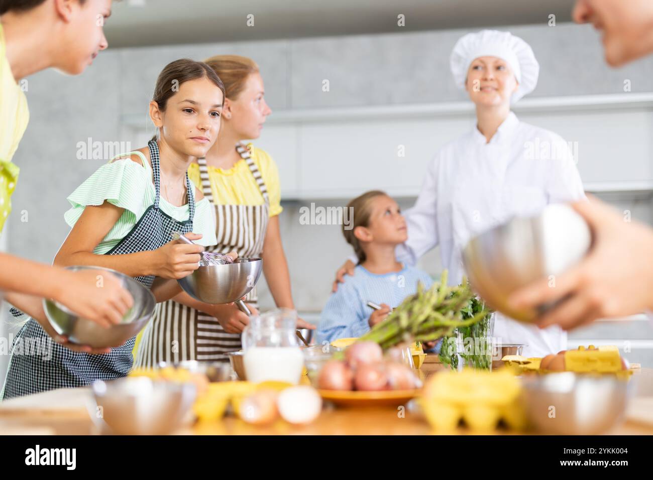 While cooking classes, teen girl stands on other side of table from ...