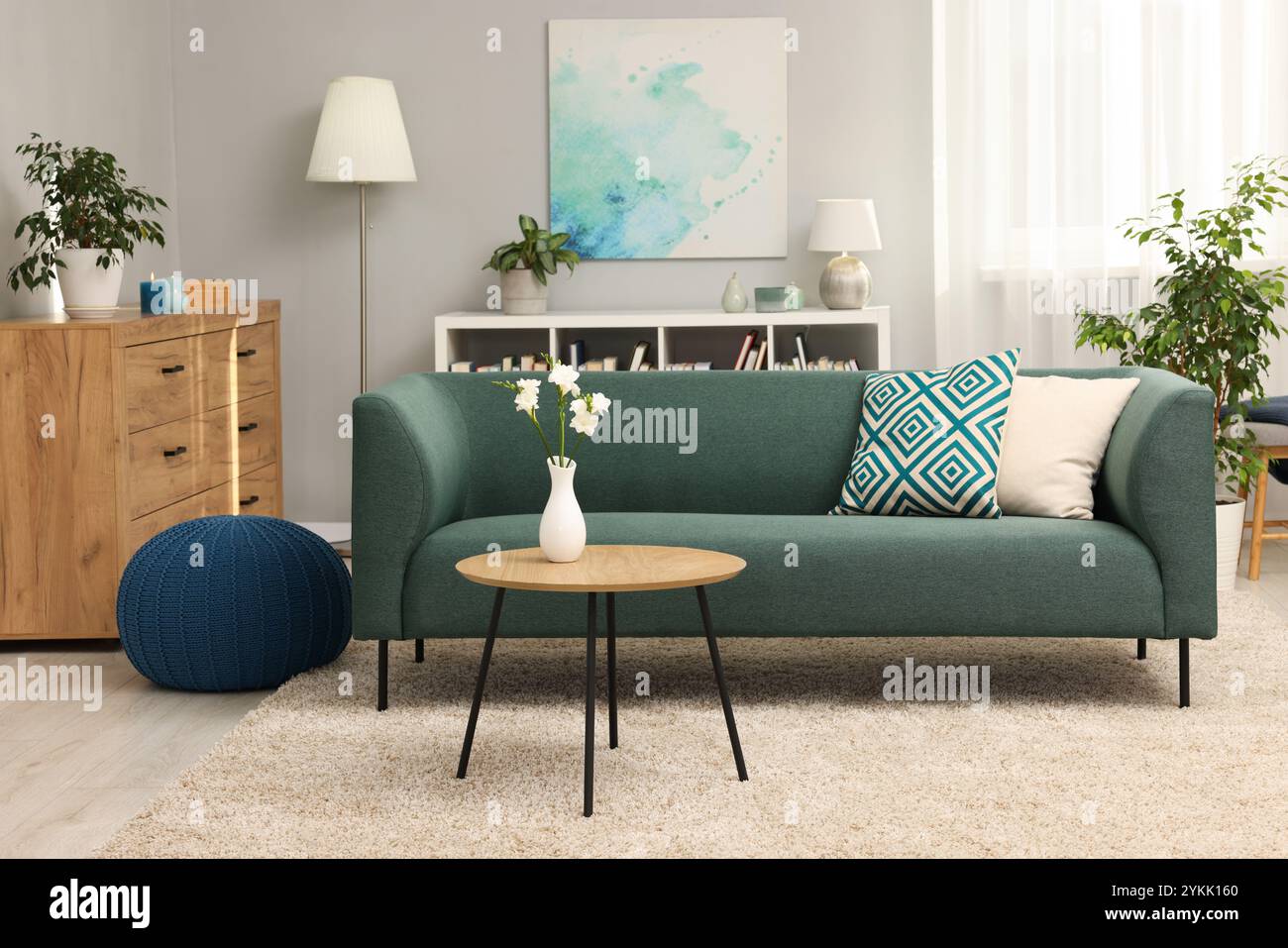 Soft sofa, coffee table, pouf, houseplants and chest of drawers near ...