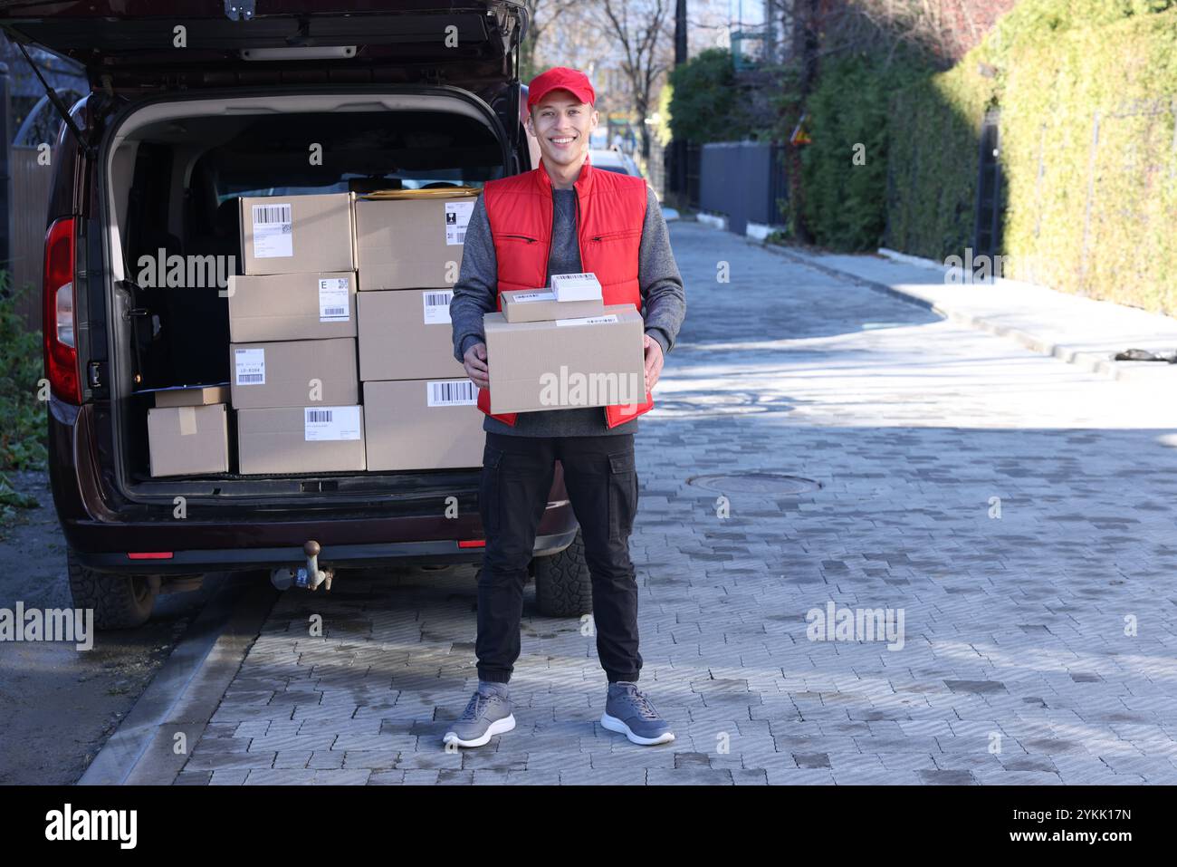 Happy postman with parcels near car outdoors Stock Photo - Alamy