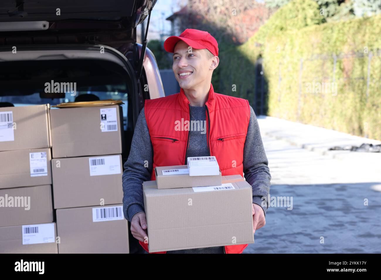 Happy postman with parcels near car outdoors Stock Photo - Alamy