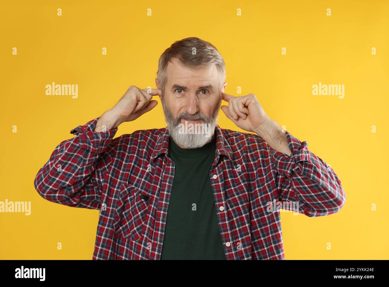 Senior man covering his ears with fingers on orange background Stock ...