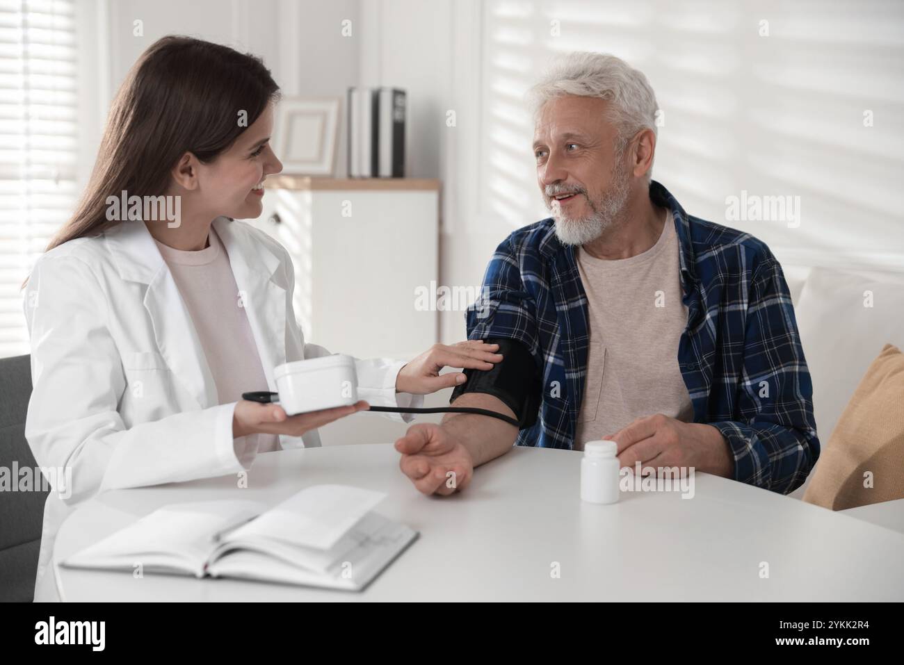 Doctor measuring patient's blood pressure at table in hospital Stock ...