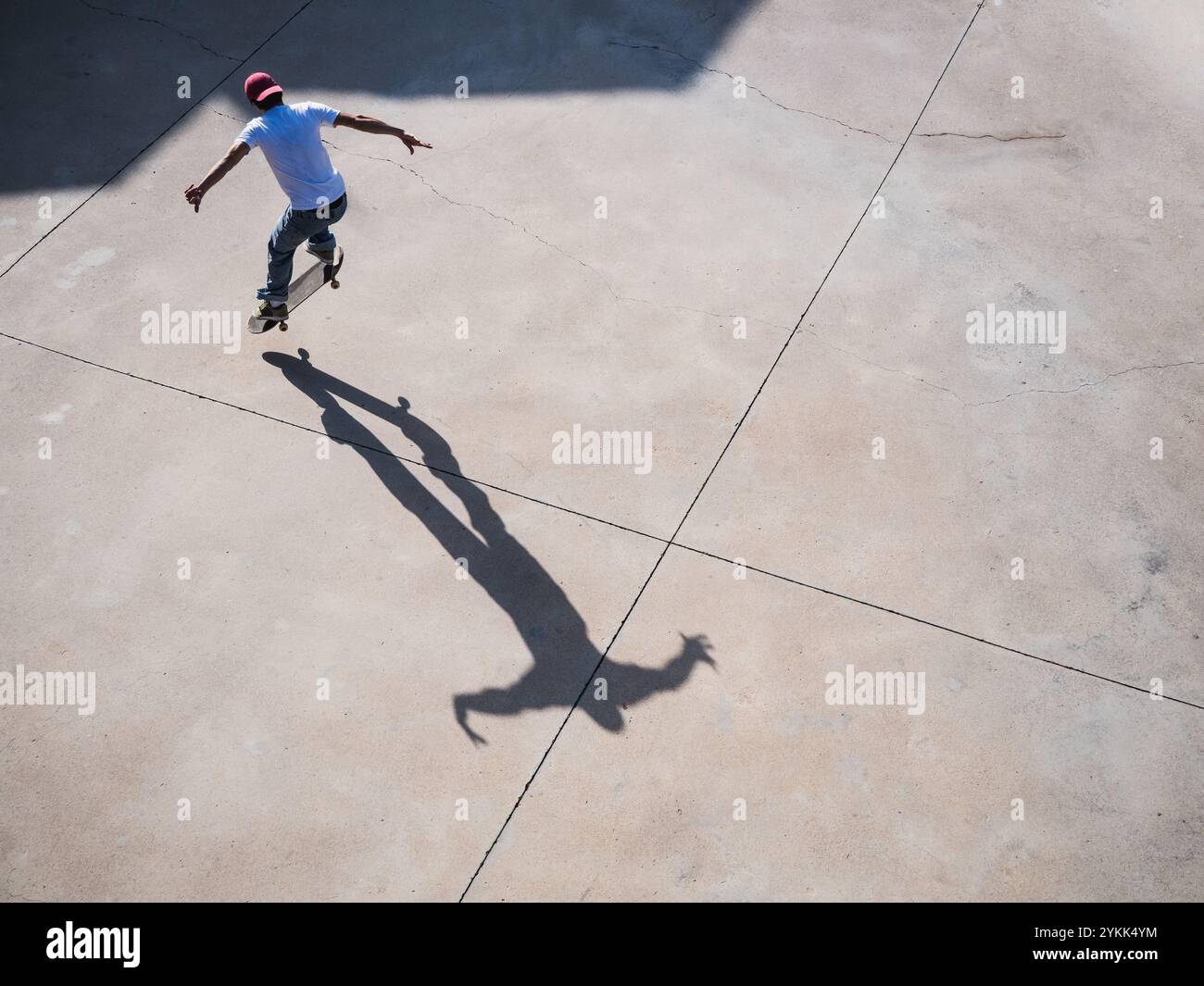 Skateboarder jumping mid-air, casting a striking shadow on a concrete ...