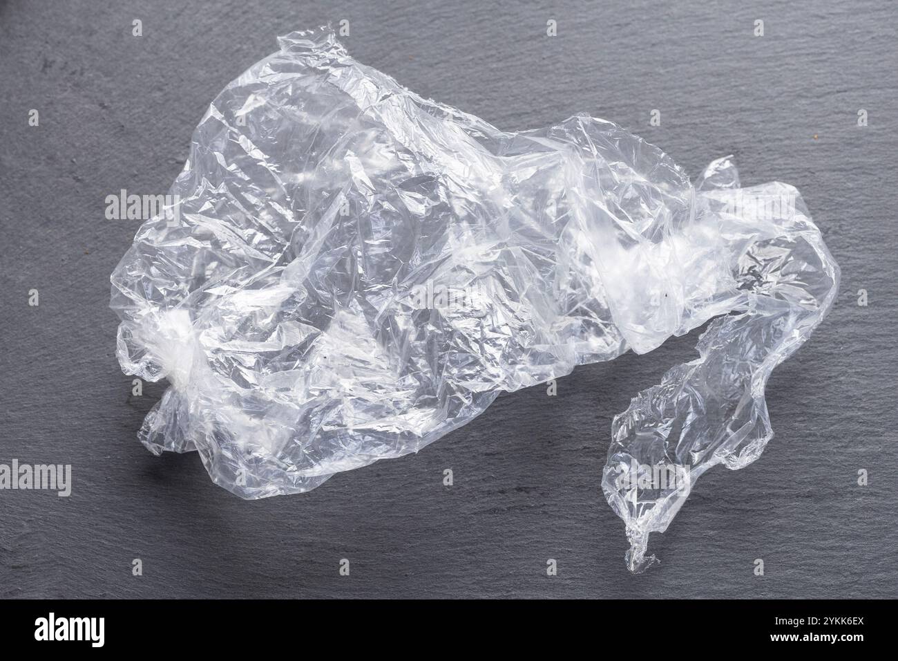 In the image you can see a crumpled and curled plastic bag on a dark ...