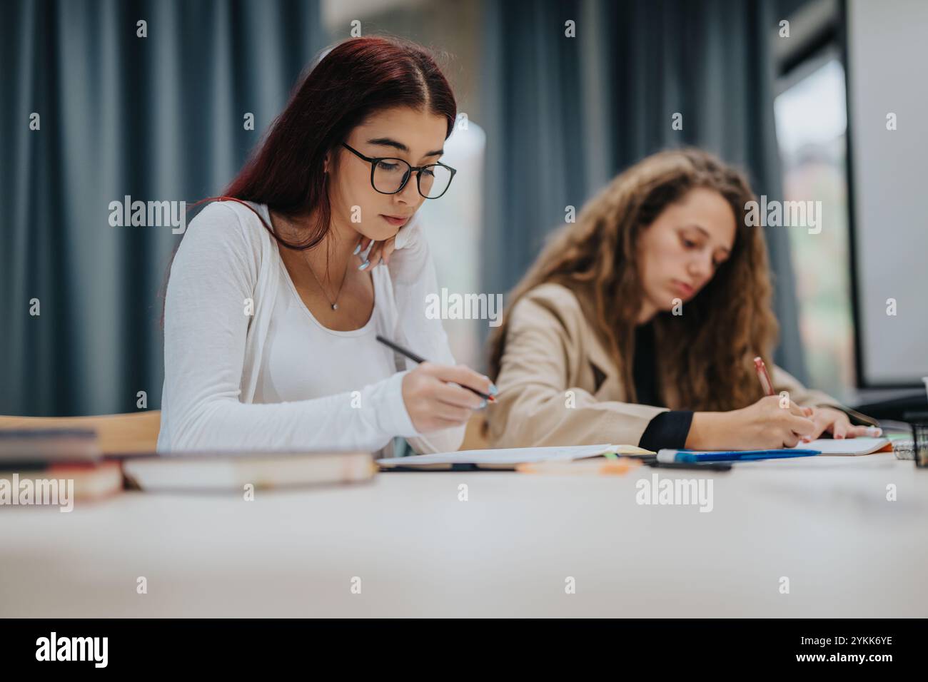 Two female students focusing on their writing assignments in class ...