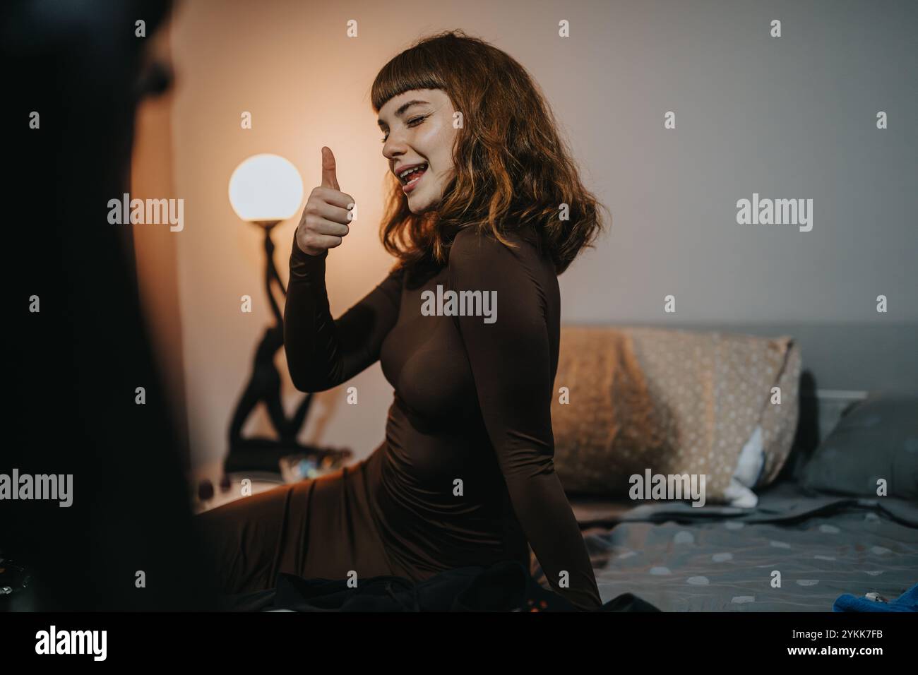 Woman giving thumbs up while getting ready for night out Stock Photo ...