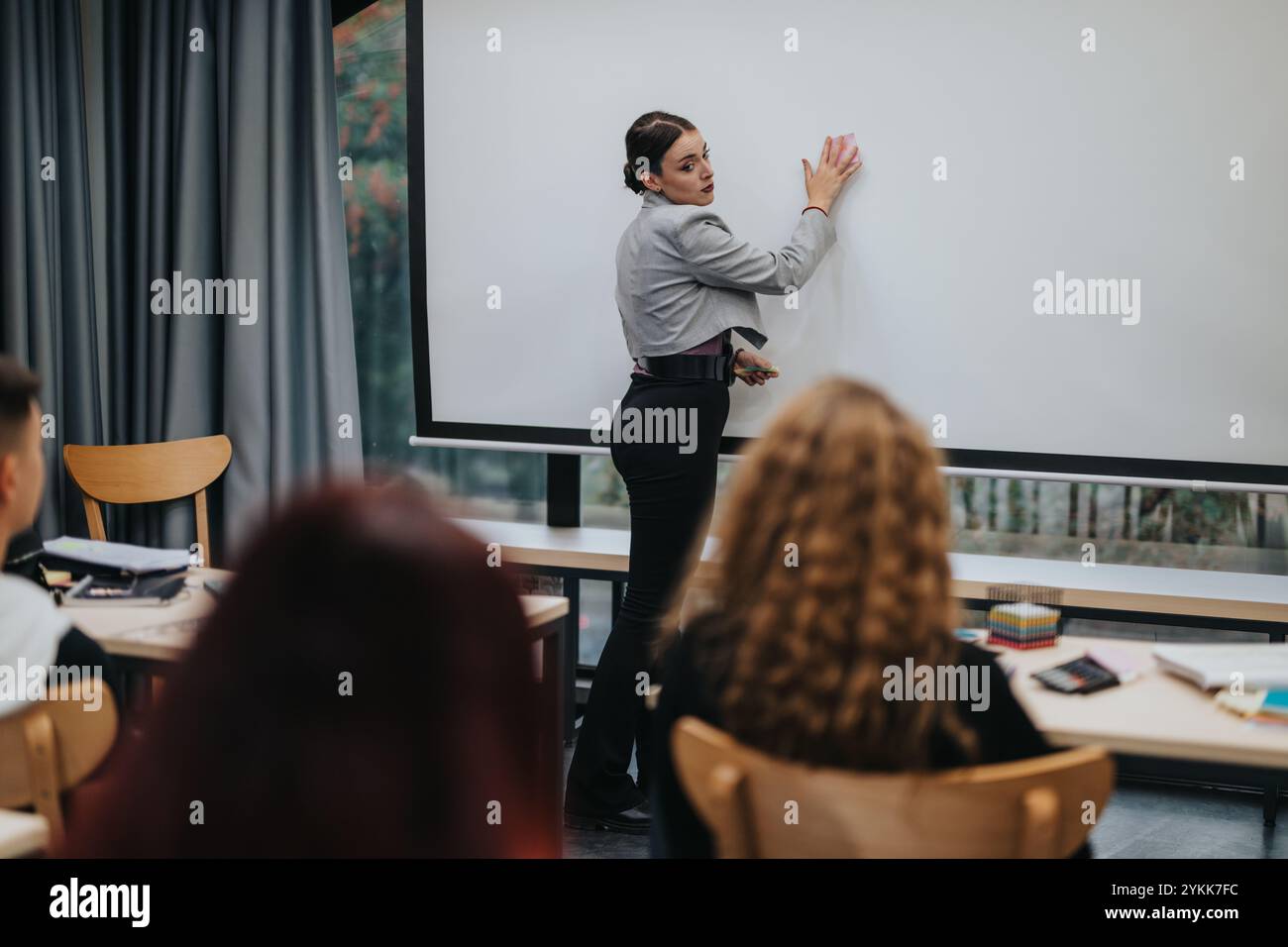 Teacher explaining concepts on whiteboard in modern classroom Stock ...