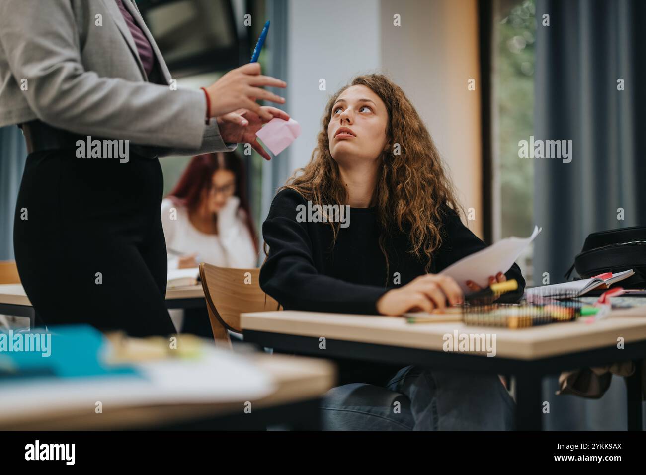 Student focused in classroom while teacher instructs discussion Stock ...
