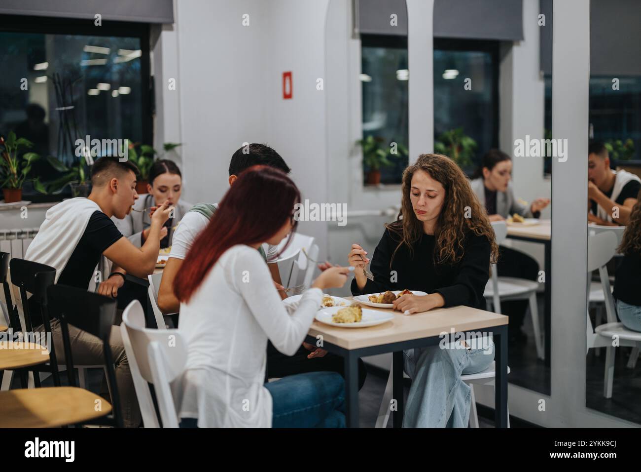 Students enjoying lunch at a school cafeteria, engaging in conversation ...