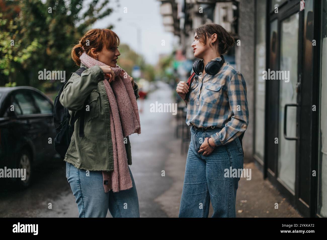 Two women chatting casually on a city sidewalk Stock Photo - Alamy