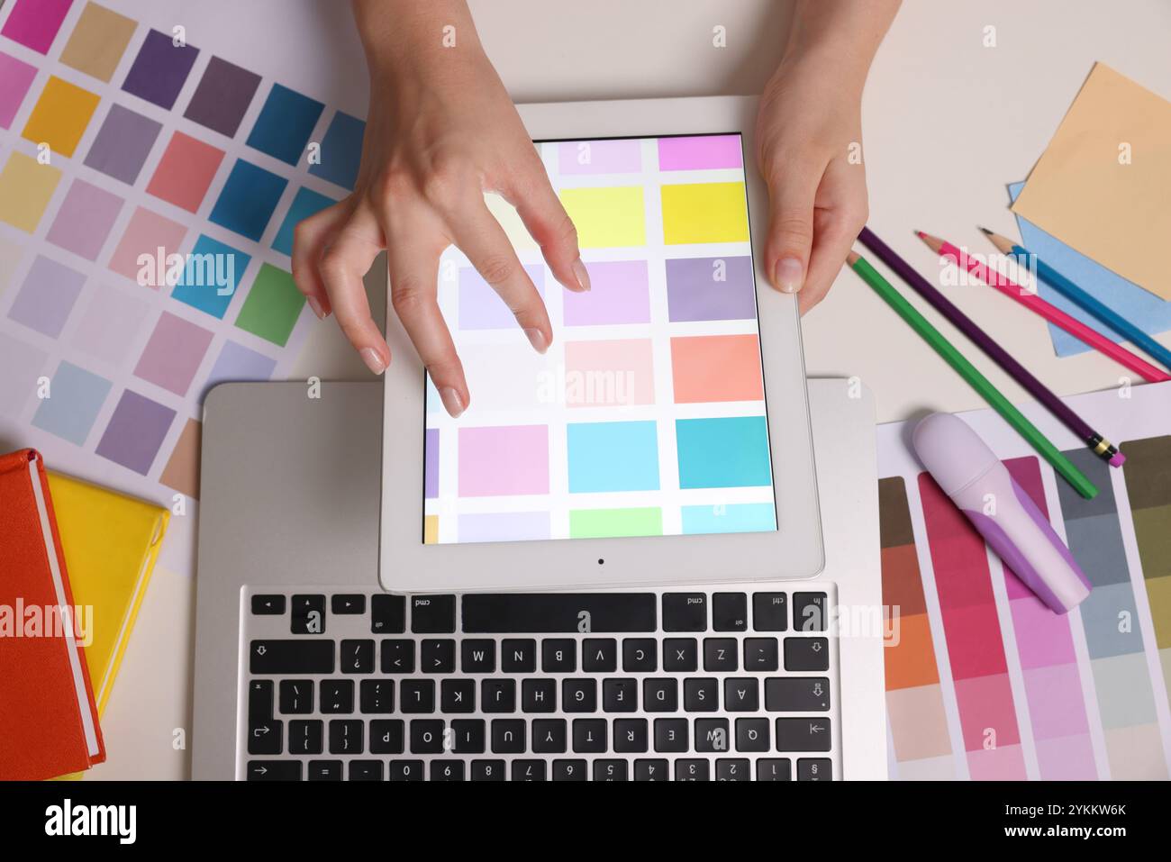 Website designer working with color palette on tablet at white table ...