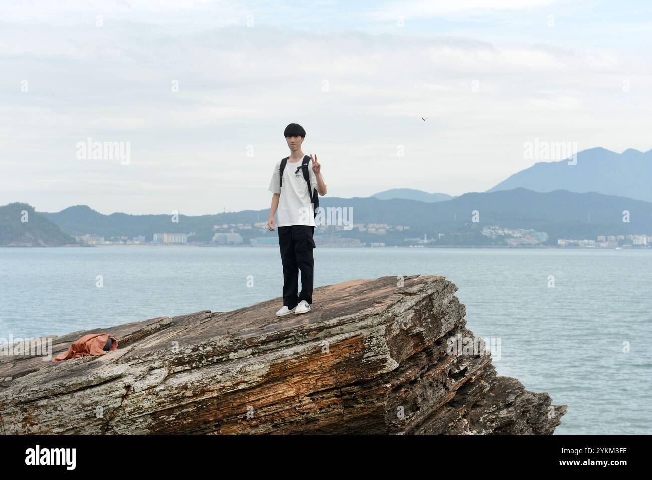 A tourist posing from the top a large rock on the southern coast of ...