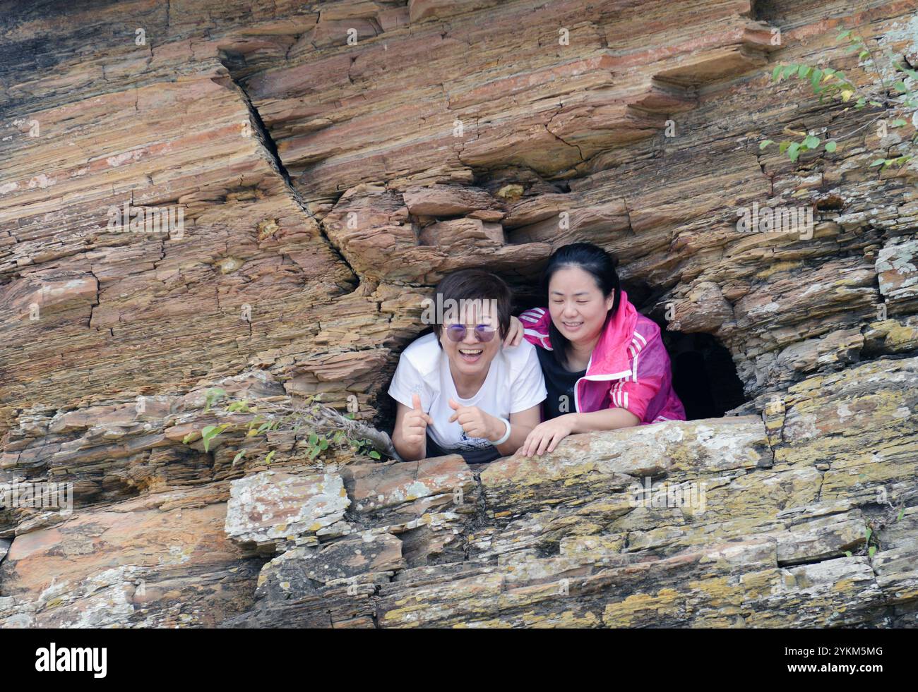 Tourist posing for a picture from a tiny cave. Tung Ping Chau island ...
