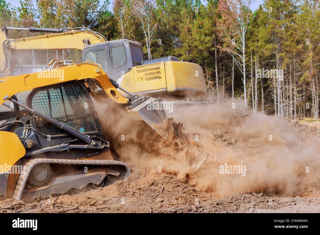 Heavy backhoe large bulldozer machines work together to clear forested ...