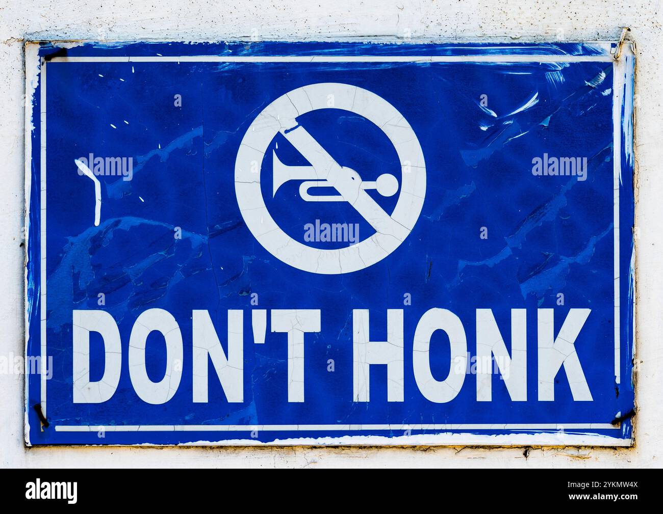 A weathered 'don't honk' traffic sign with a nohorn symbol, on a wall ...