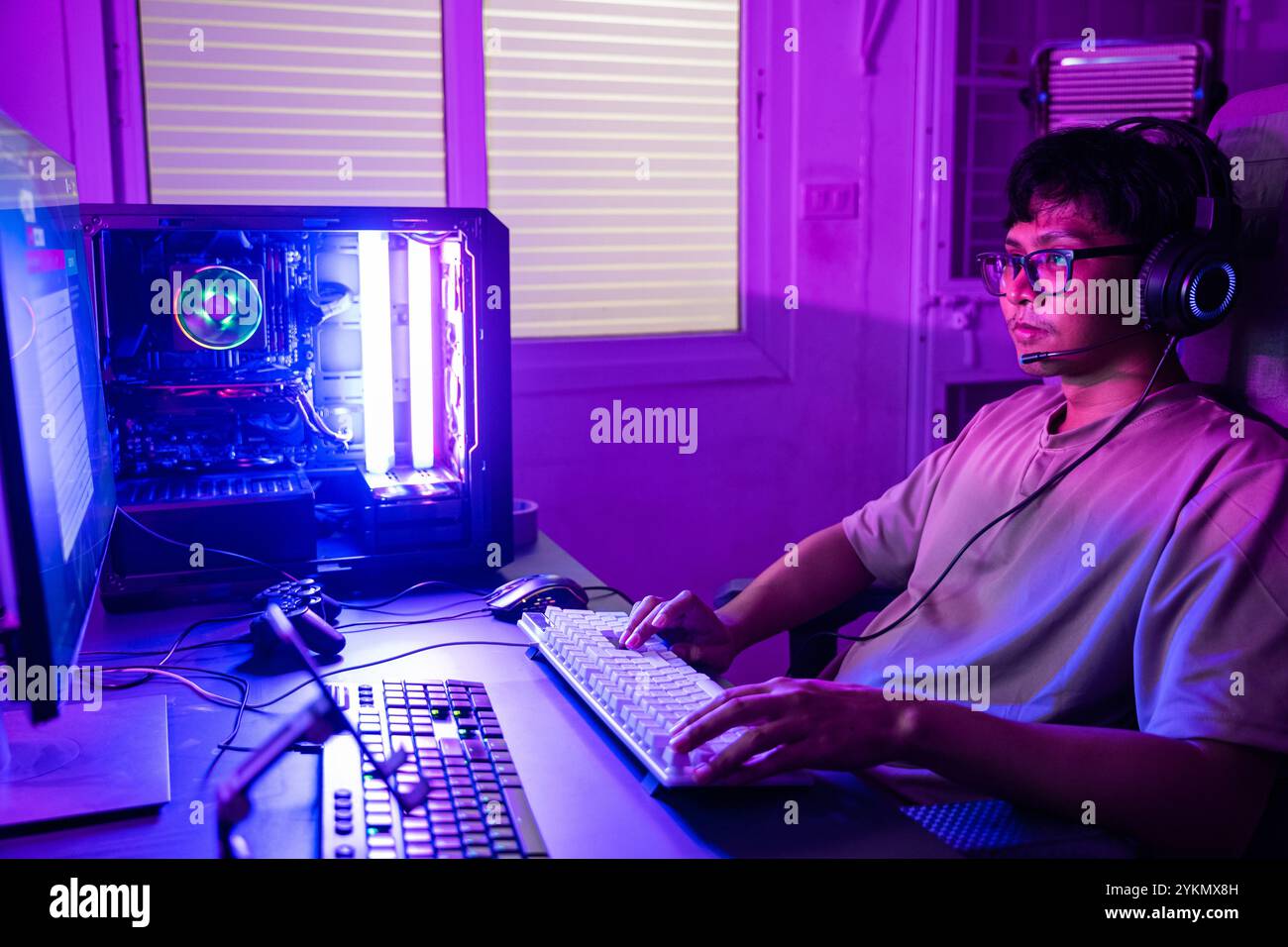 Young Asian man gamer wearing glasses and headphones playing a video ...