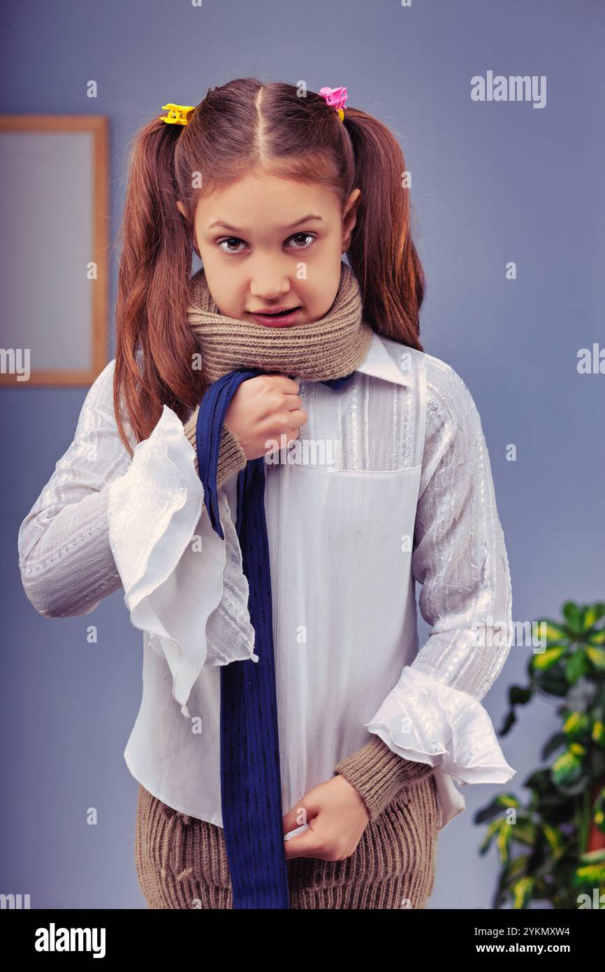 Elementary age girl with two ponytails is wearing two scarves, a beige ...