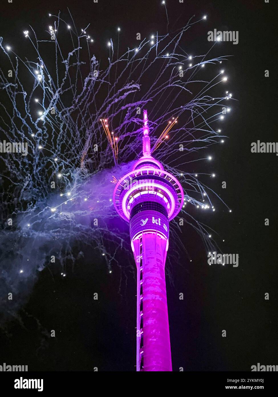 Vibrant fireworks show bursting around a brightly lit tower against a ...