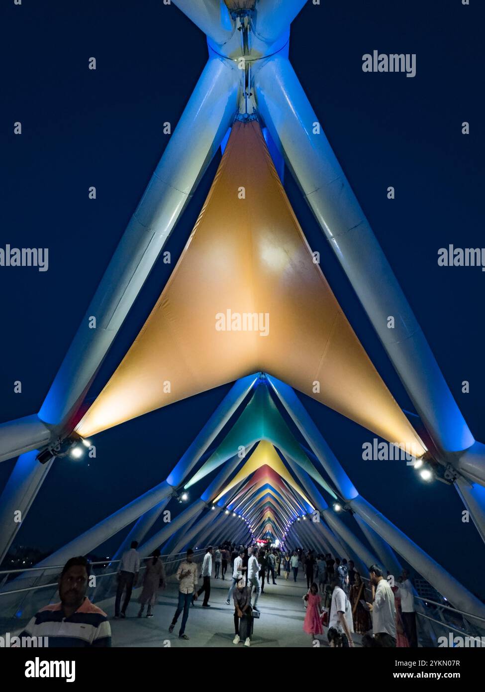 Illuminated modern bridge with people walking at dusk, showcasing ...