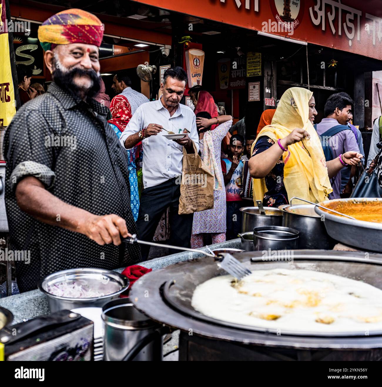 Indian chef prepares traditional food at a bustling street market stall ...