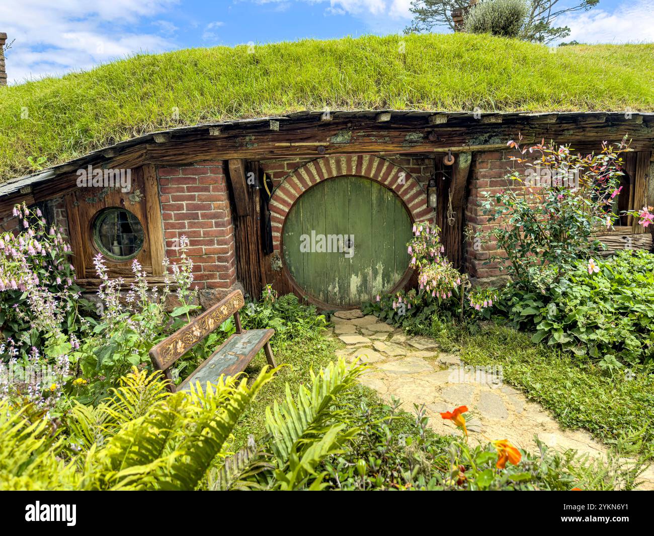Cozy hillside hobbit house with green roof and wooden circular door ...