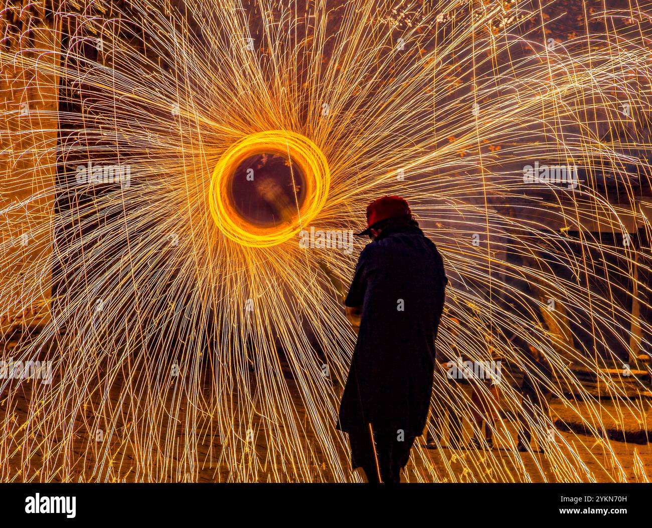Street artist spinning burning steel wool creating a circle of sparks ...