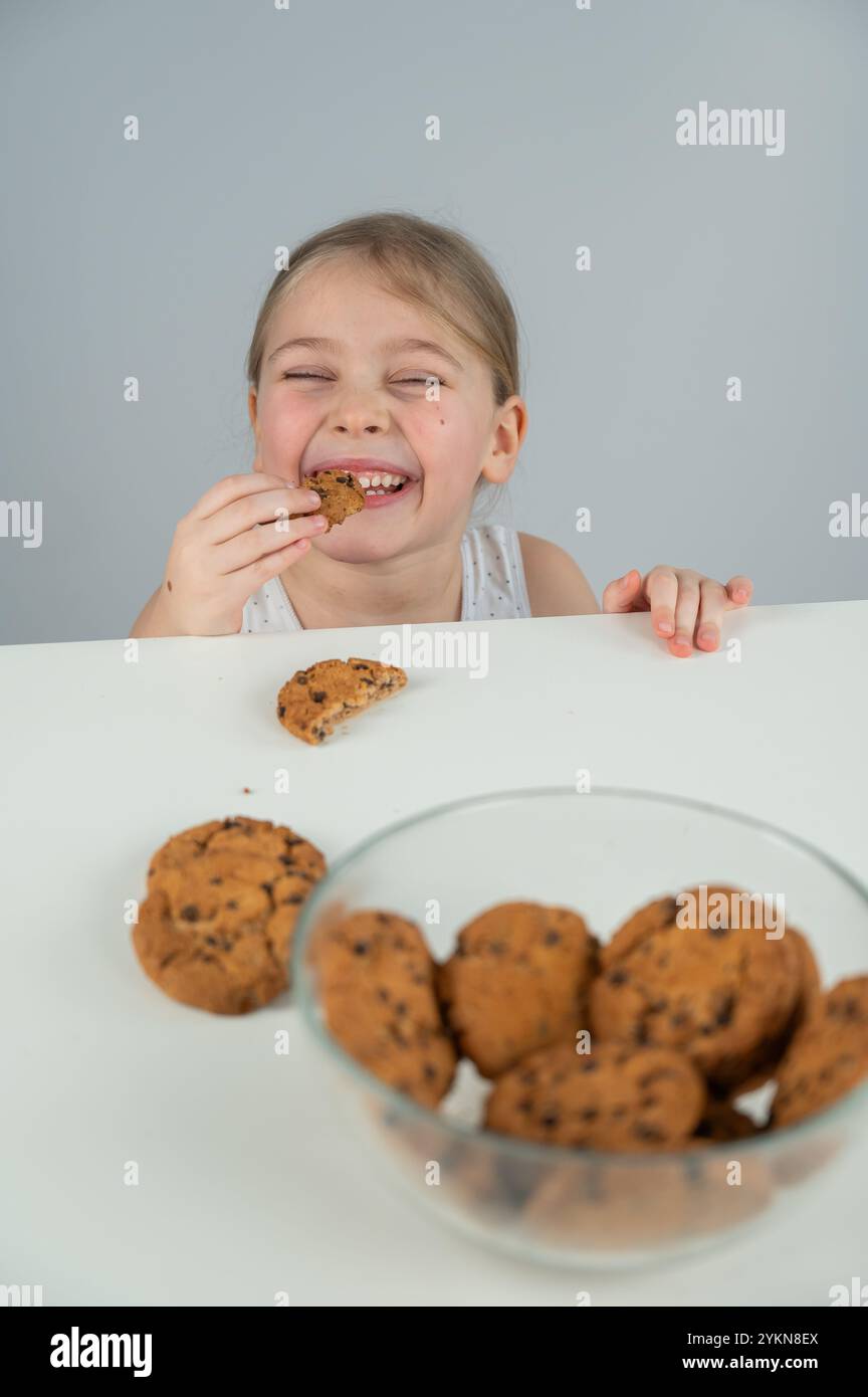 A little girl steals cookies from the table. Vertical photo Stock Photo ...