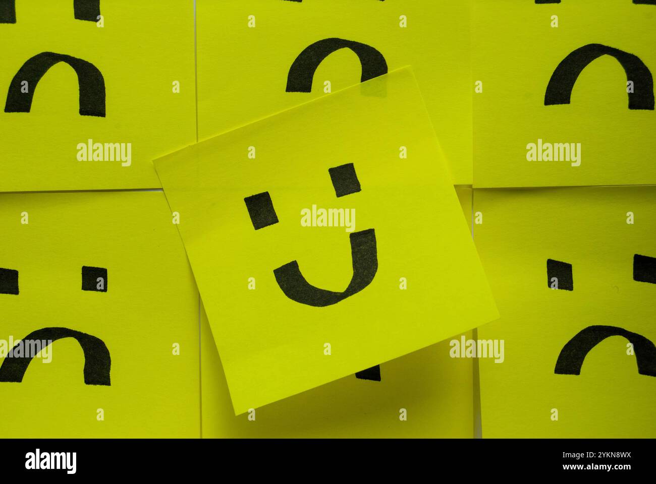 Sad face stickers surrounding a single happy face sticker, symbolizing ...