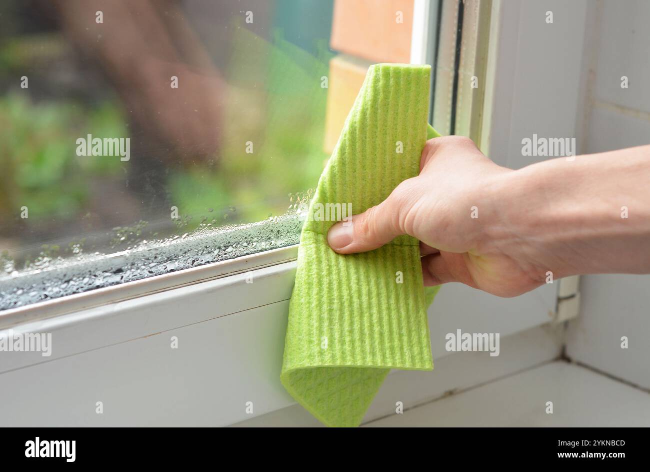 Woman hand wipes off water condensation on white window in bathroom ...