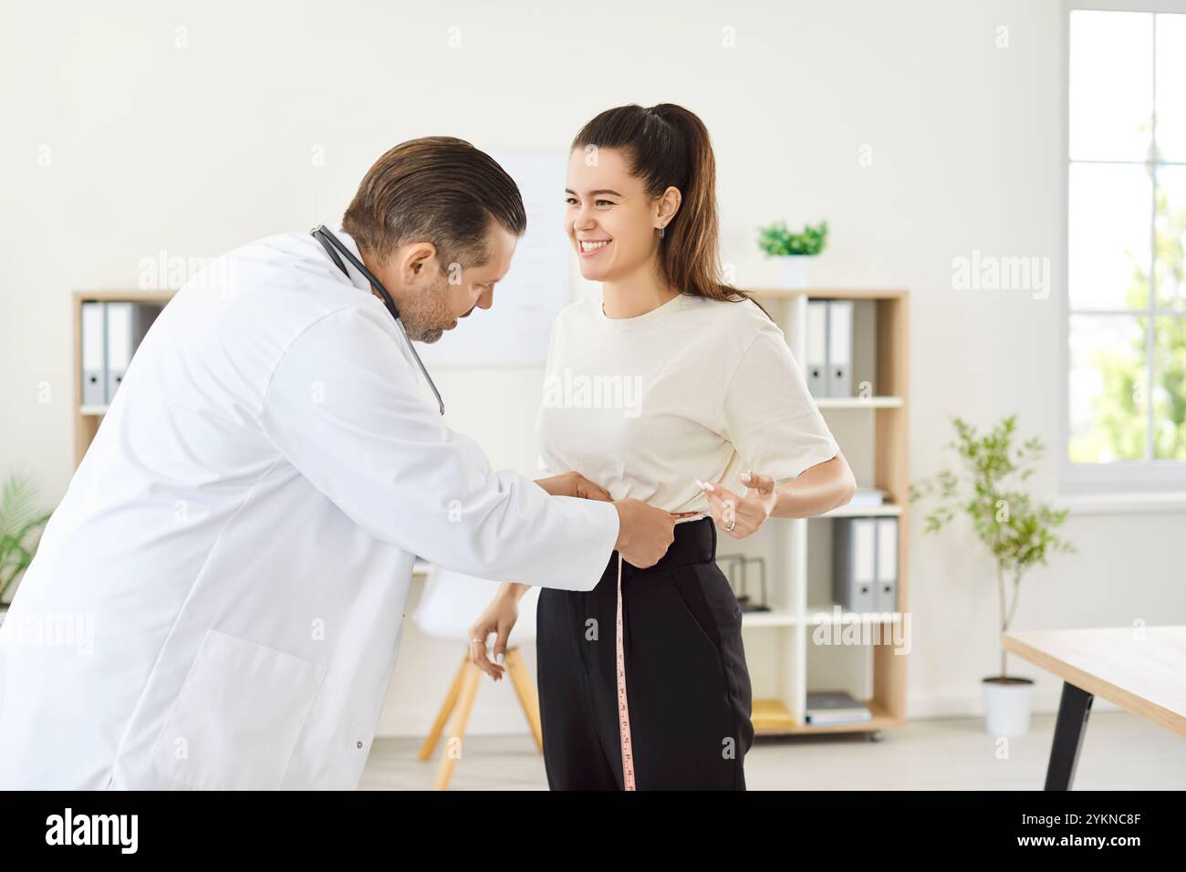 Male doctor, nurse doing measure waist using tape measure, taking young ...