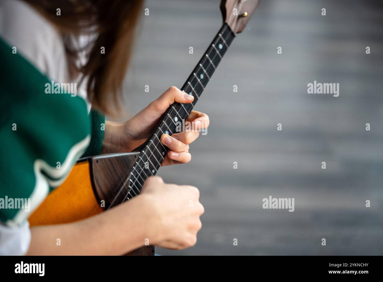 Girl playing on Russian balalaika, closeup of finger touches the string ...