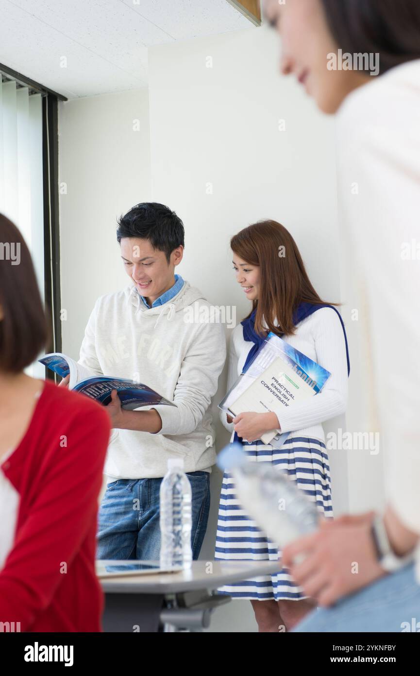 Four university students, male and female, chatting and laughing in a ...