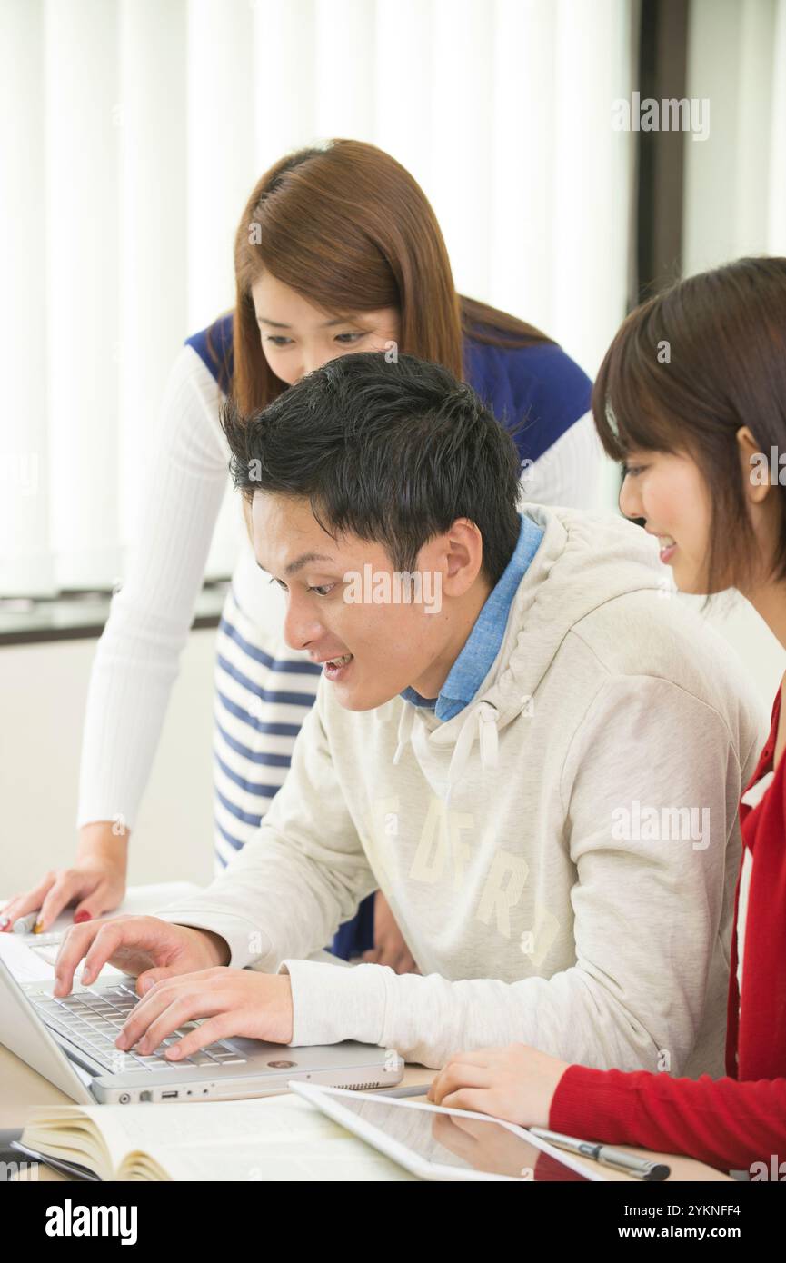 Three university students, male and female, studying in a lecture room ...