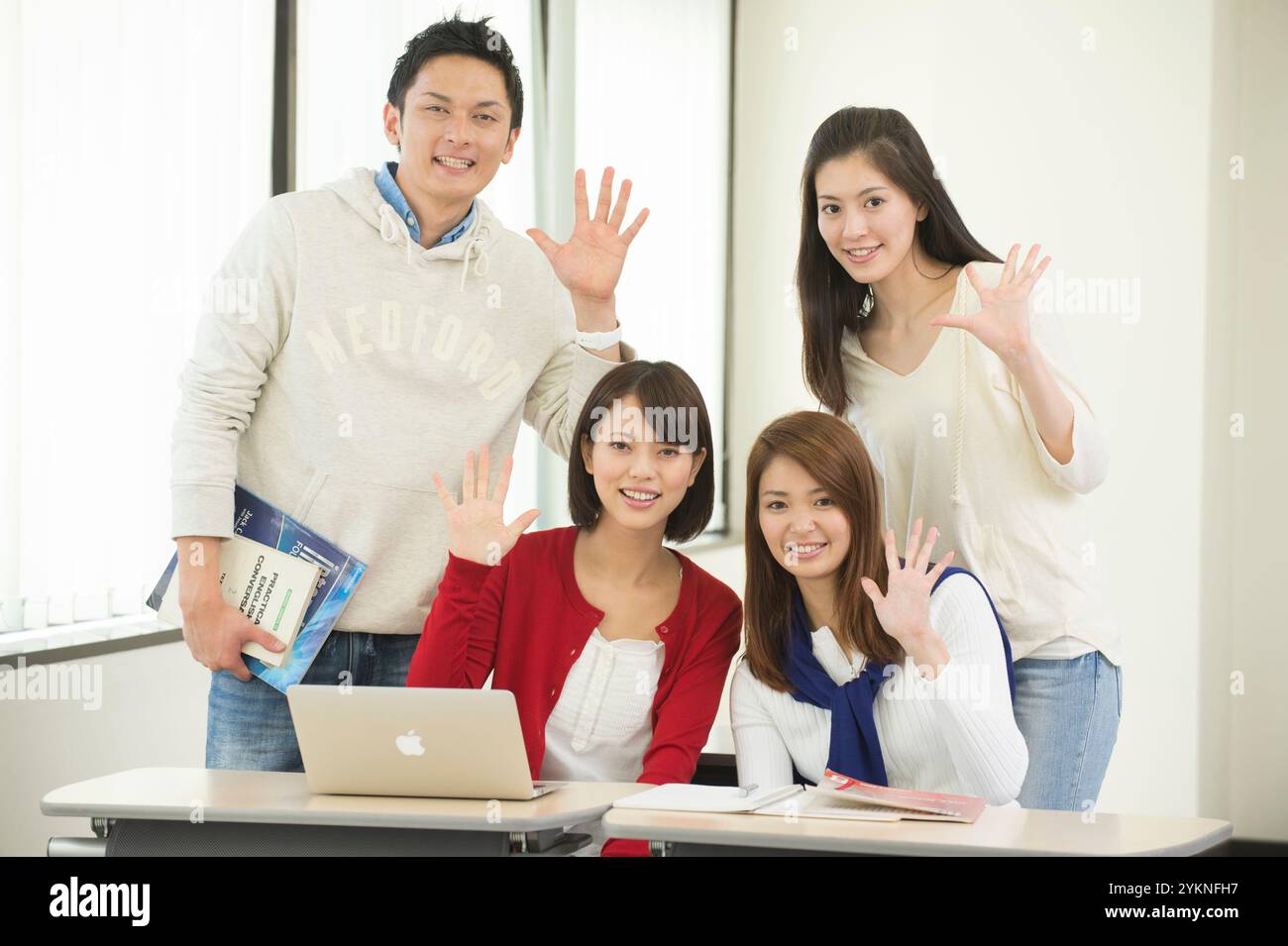 Four university students, male and female, waving to each other in a ...