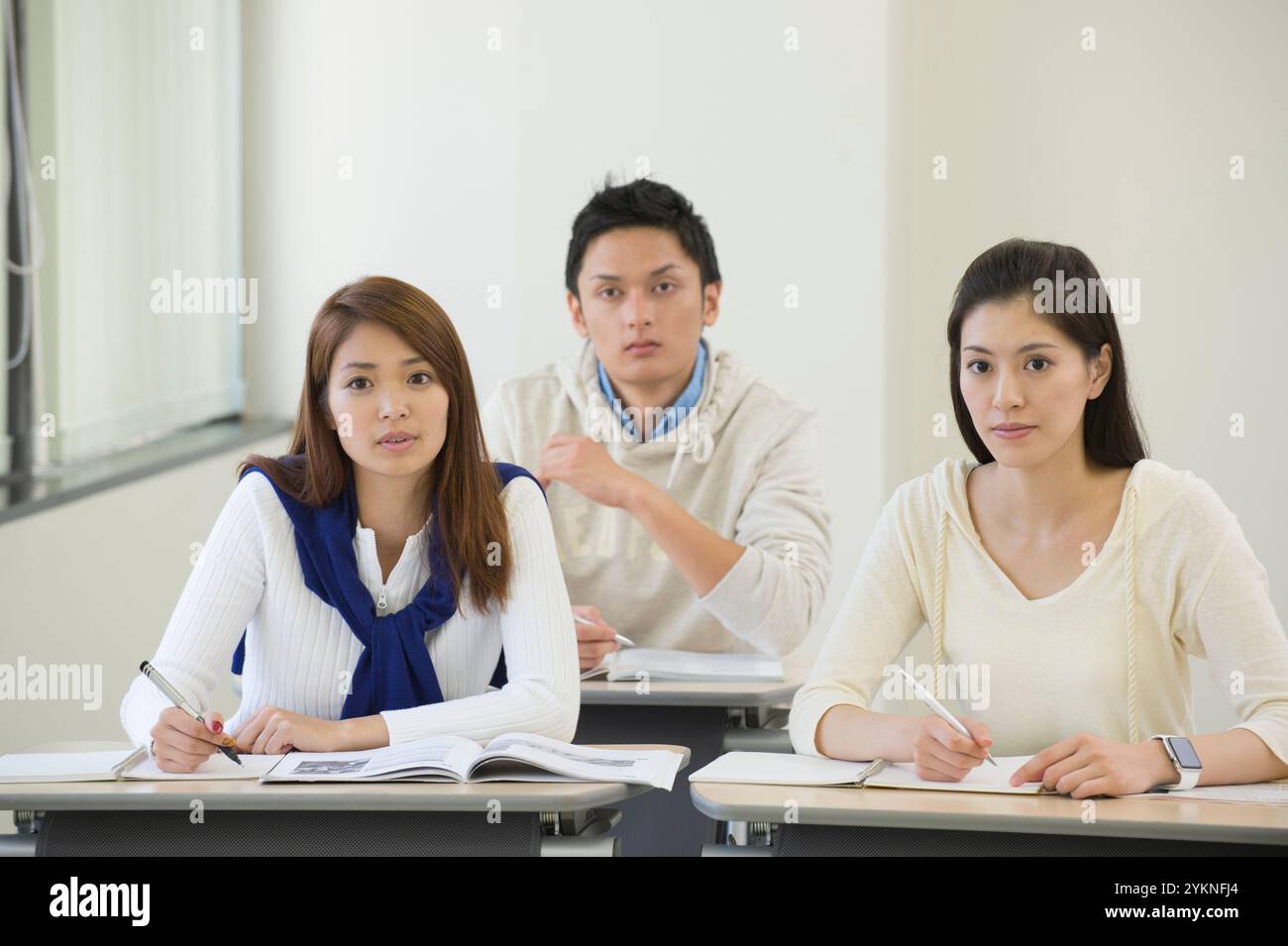 Three university students, male and female, during a lecture Stock ...