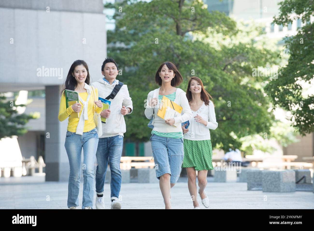 Four university students, male and female, running on campus Stock ...