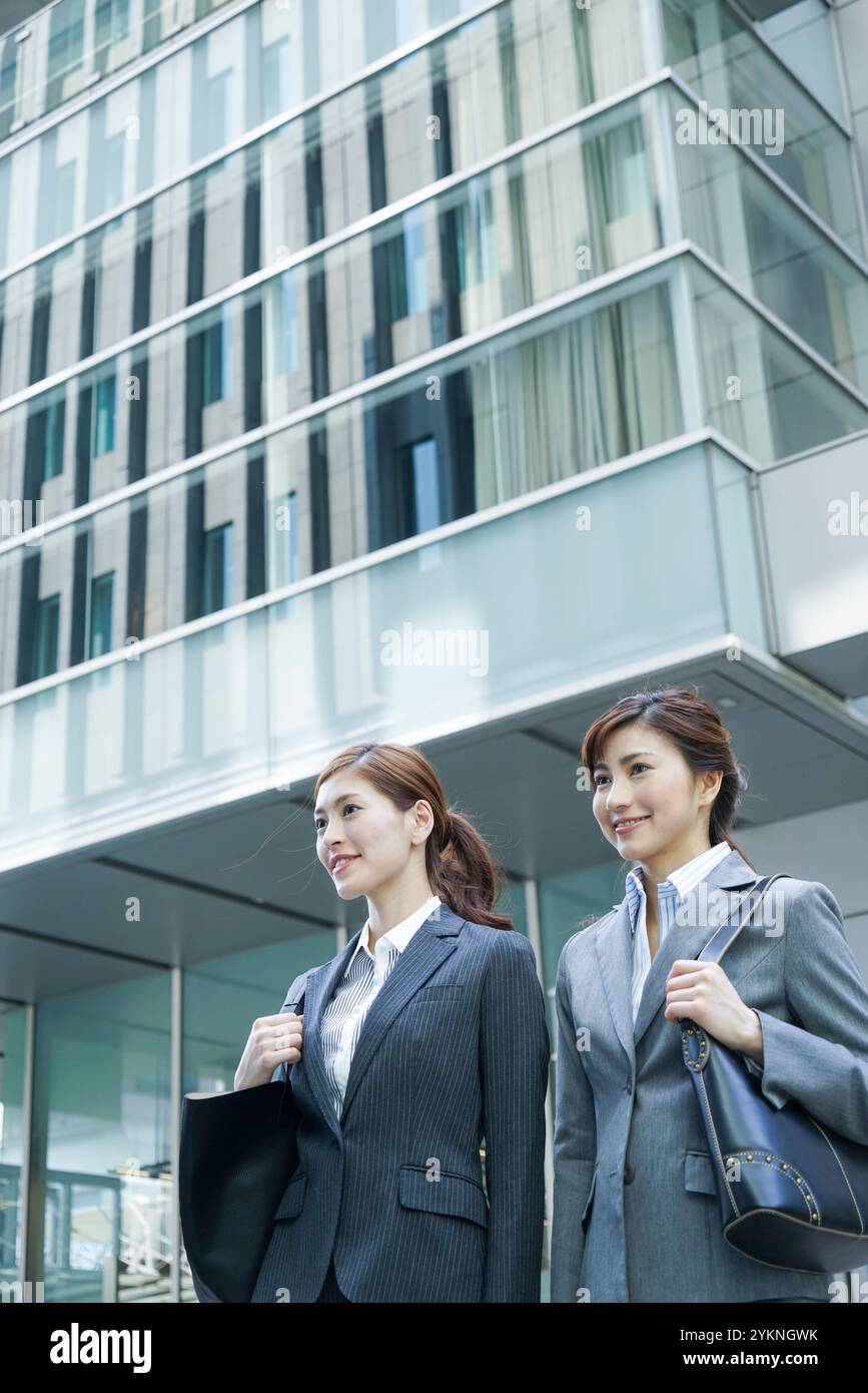 Two office workers walking through office building Stock Photo - Alamy