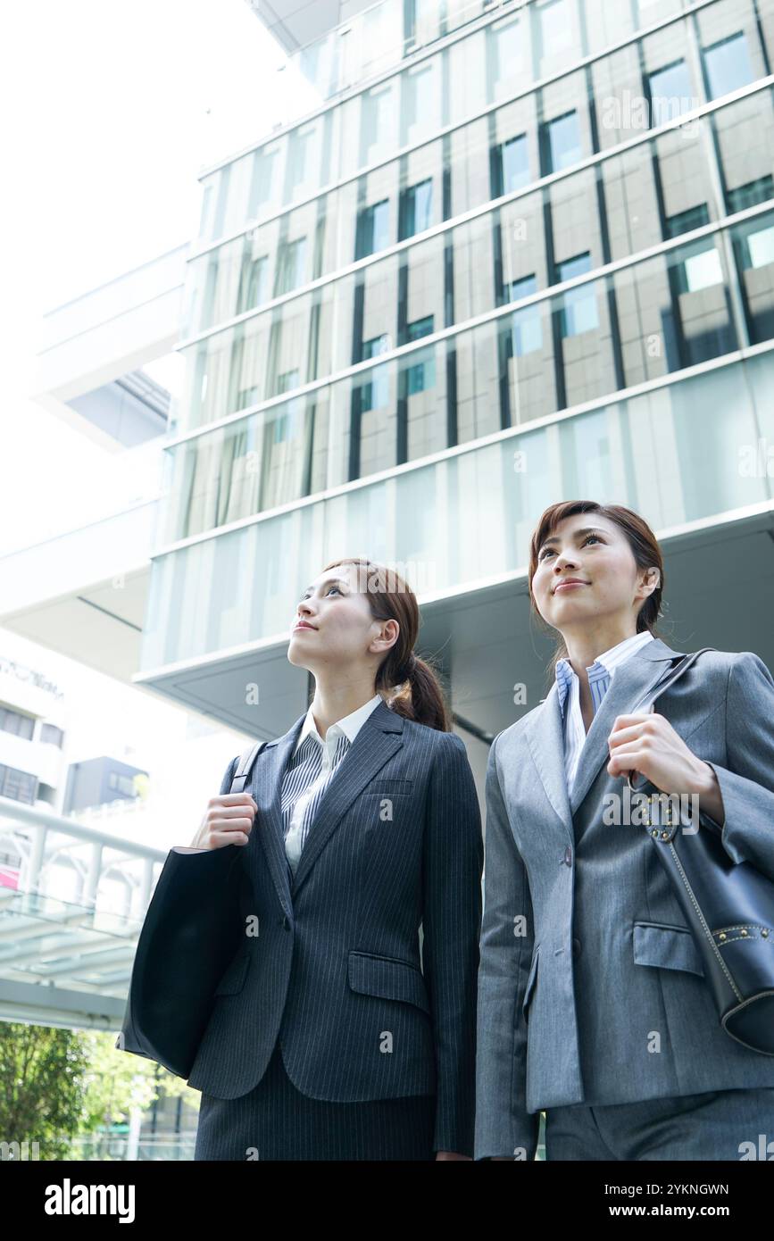 Two office workers looking up at office building Stock Photo - Alamy