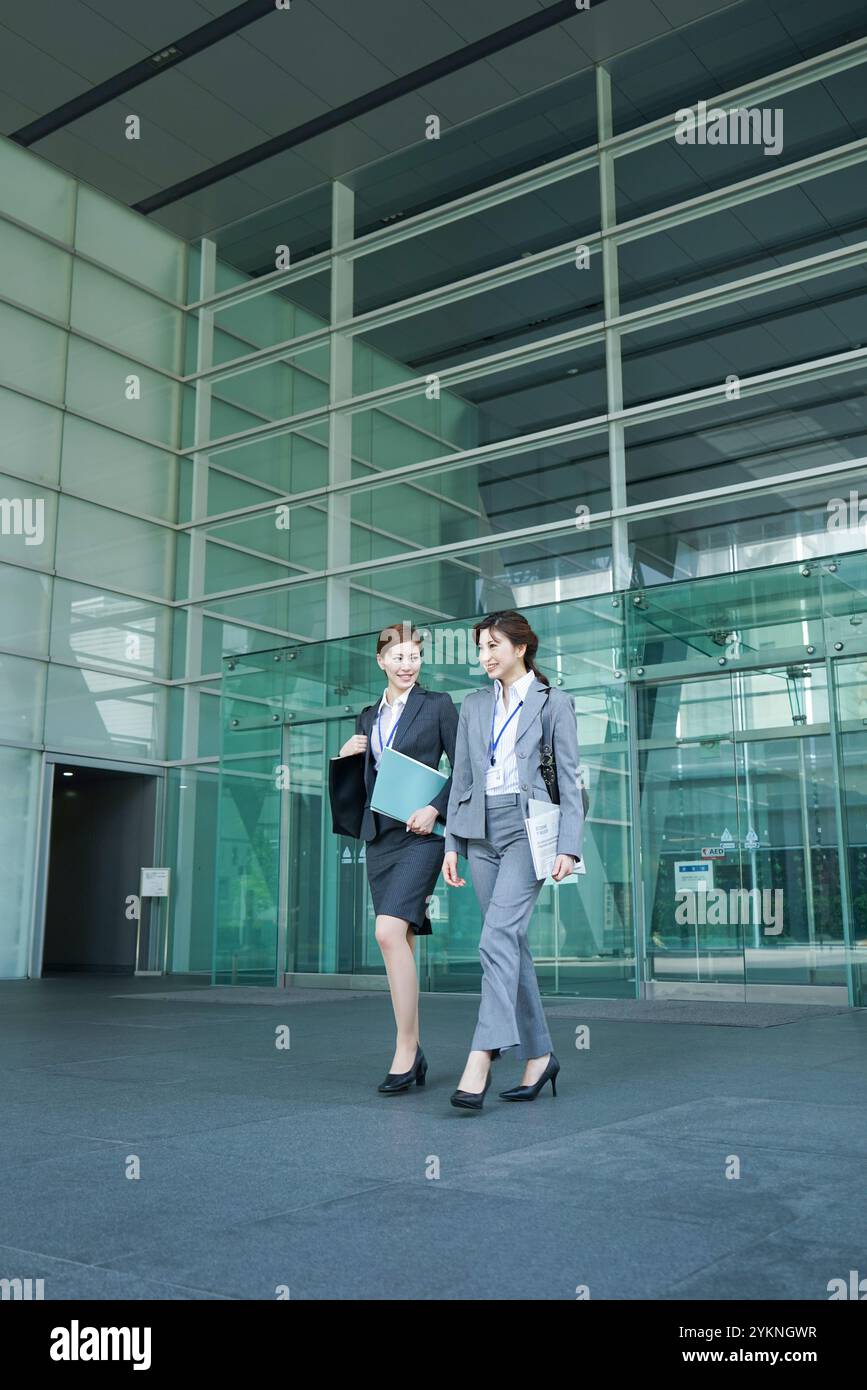 Two office workers walking through office building Stock Photo - Alamy
