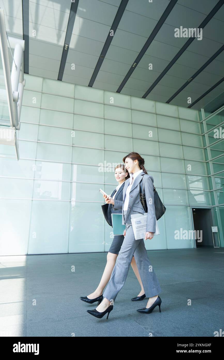 Two office workers walking through office building Stock Photo - Alamy