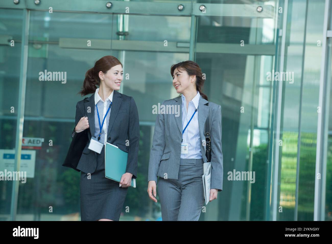 Two office workers walking through office building Stock Photo - Alamy