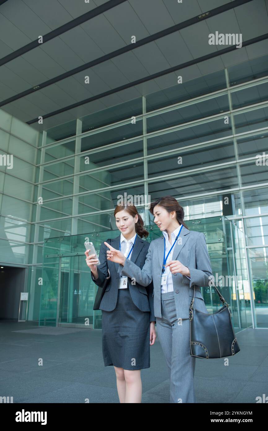Two office workers looking at their phones in an office building Stock ...