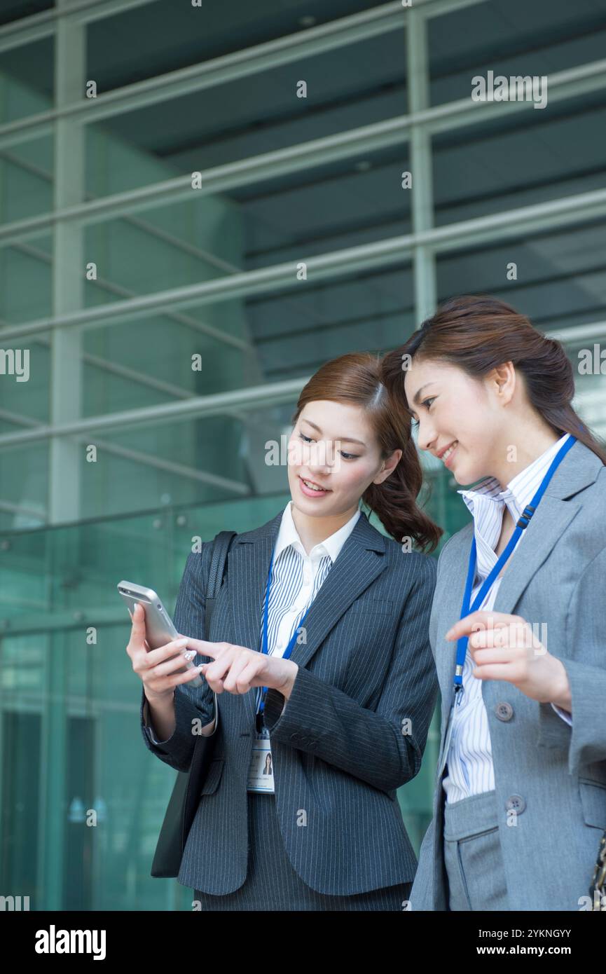 Two office workers looking at their phones in an office building Stock ...
