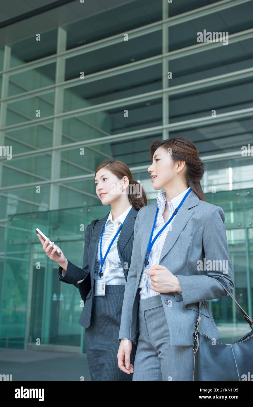Two office workers looking at their phones in an office building Stock ...